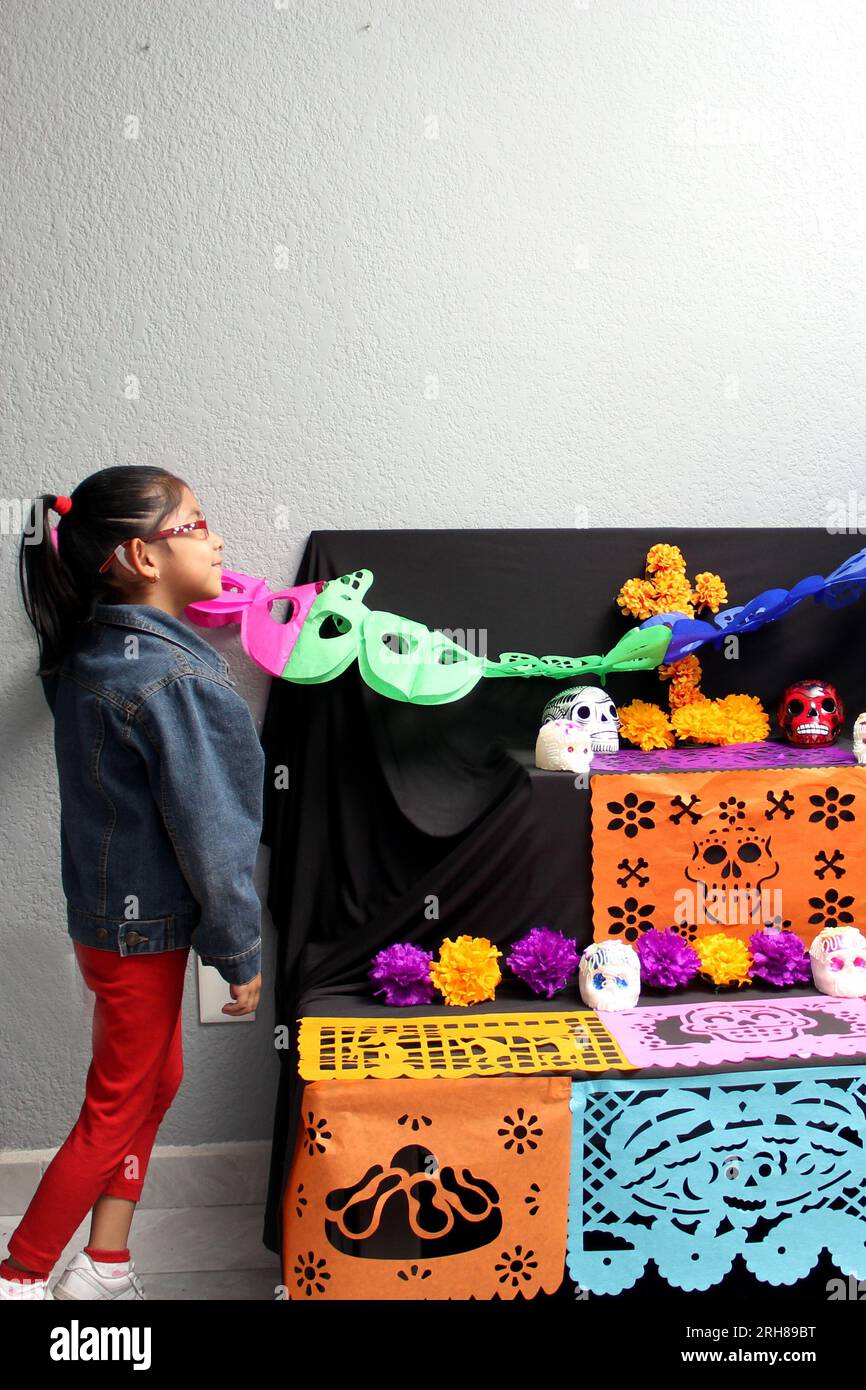 Mexican child girl put the altar and offering of the Day of the Dead in ...
