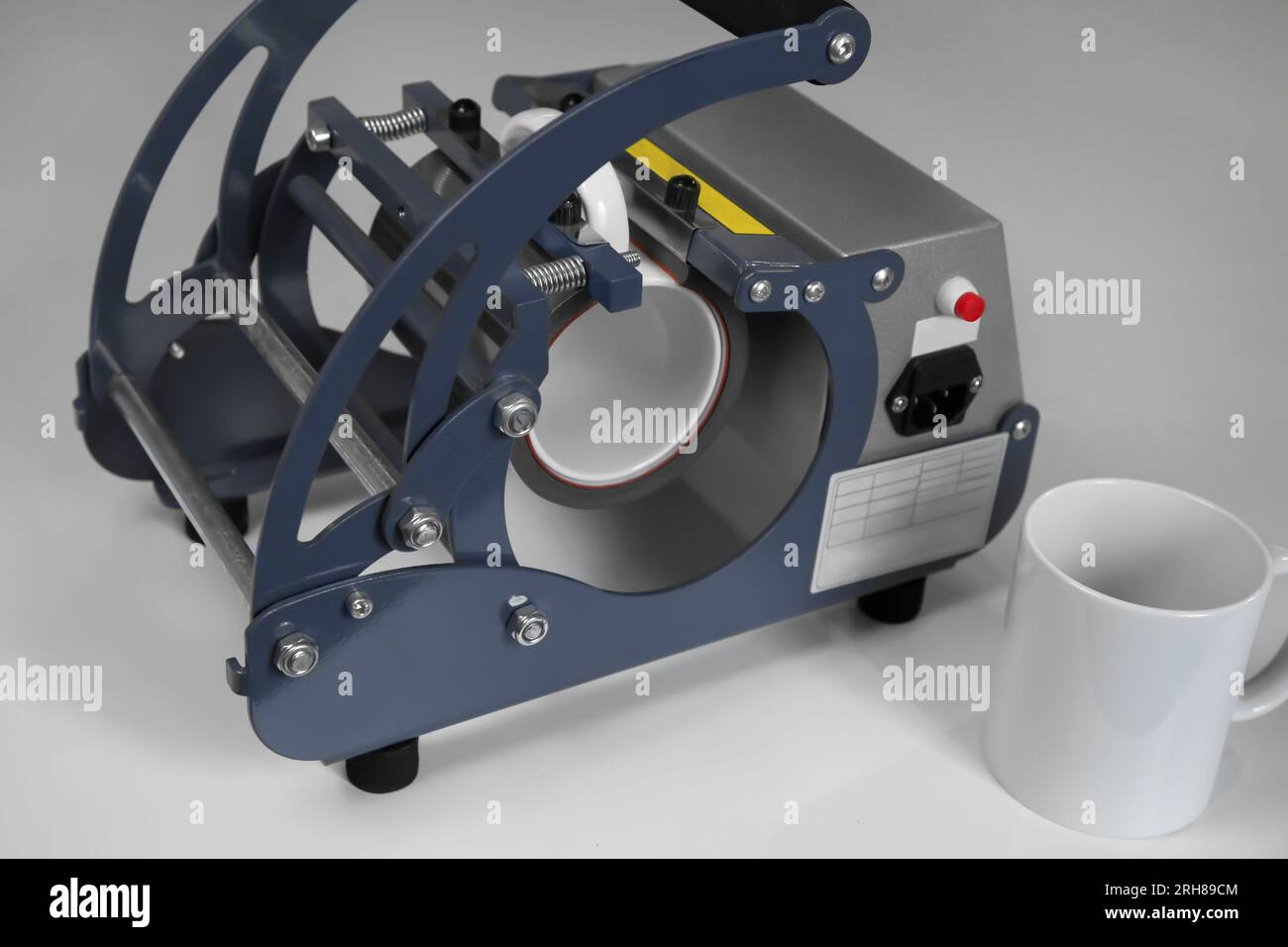 Printing logo. Heat press with cups on white table Stock Photo - Alamy