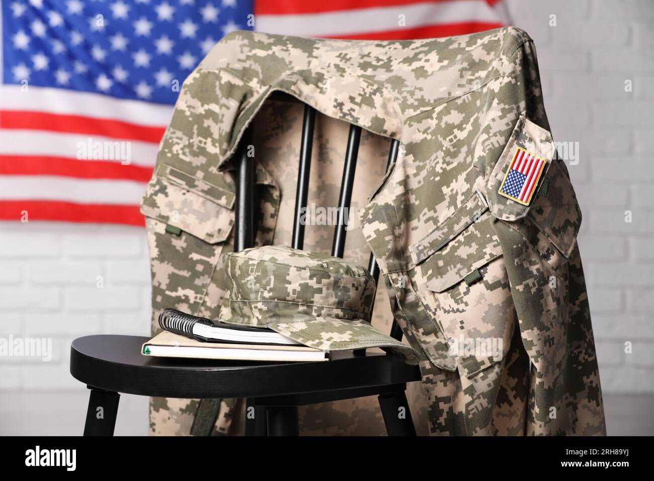Chair with soldier uniform and notebooks near flag of United States ...