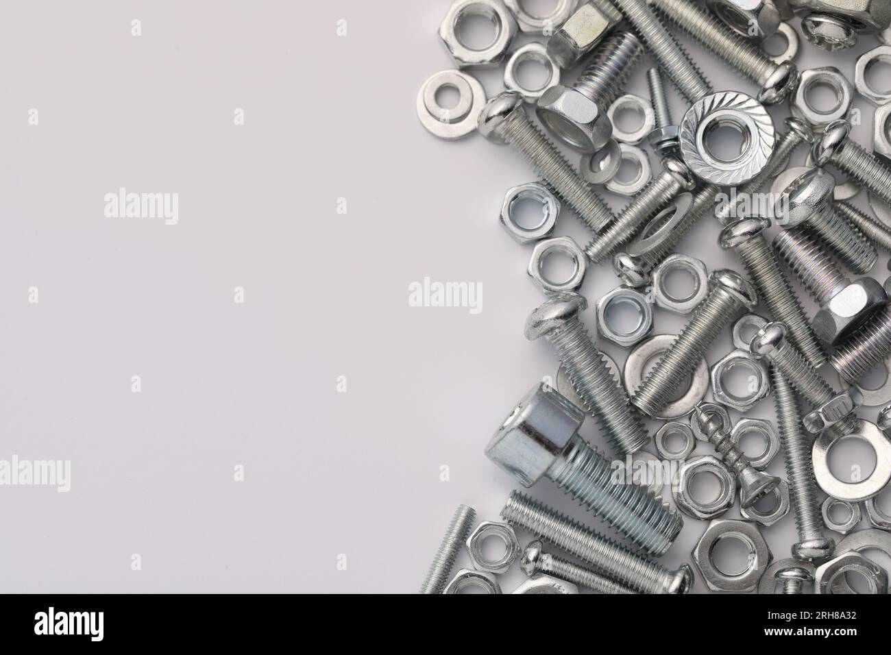 Different metal bolts and nuts on white background, flat lay. Space for ...