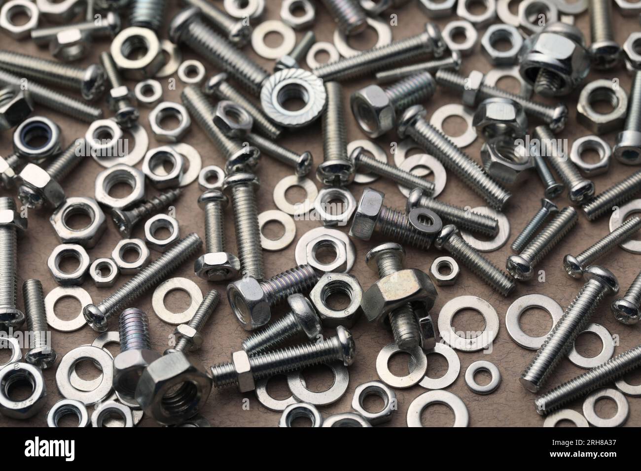 Different metal bolts and nuts on beige textured table, above view ...