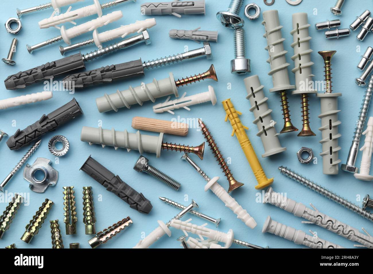 Many different fasteners and dowels on light blue background, flat lay ...