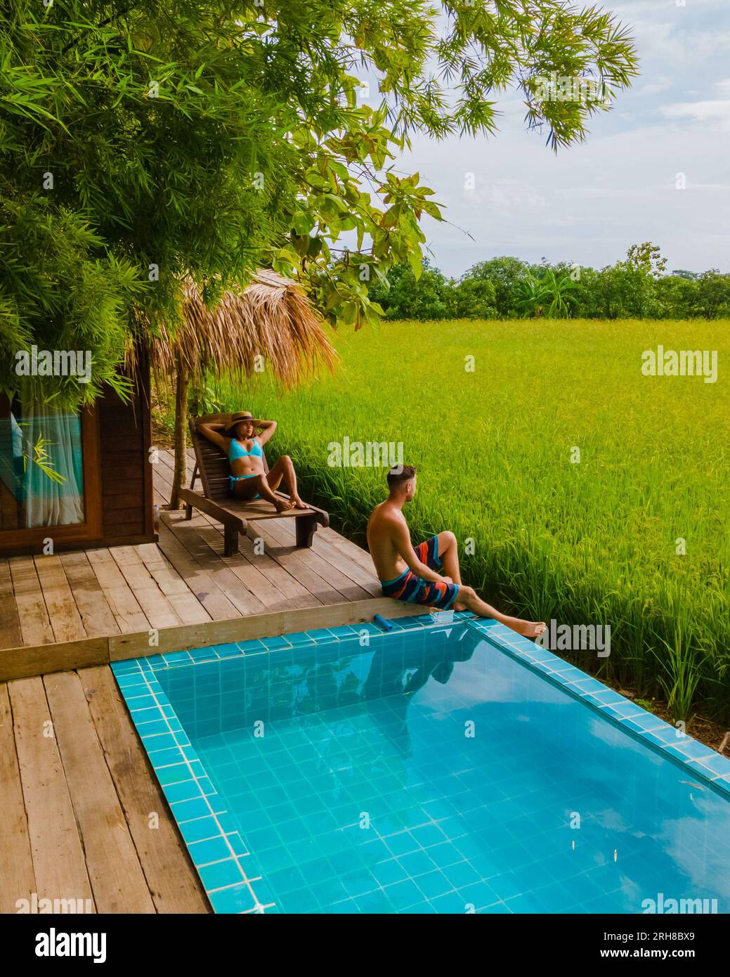 a couple of men and women in front of a Bamboo hut homestay farm, with ...