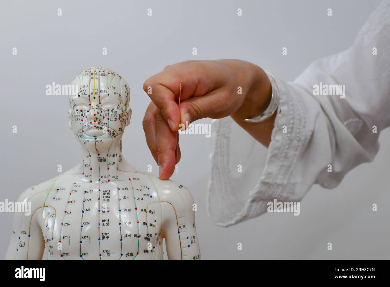 A woman hand sticking an acupuncture needle into a human dummy ...