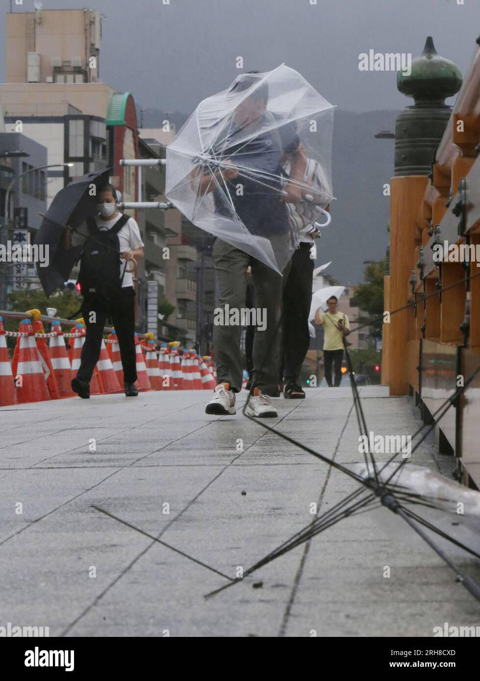 People walk on a street while Typhoon No.7 (Lan) landing the main ...