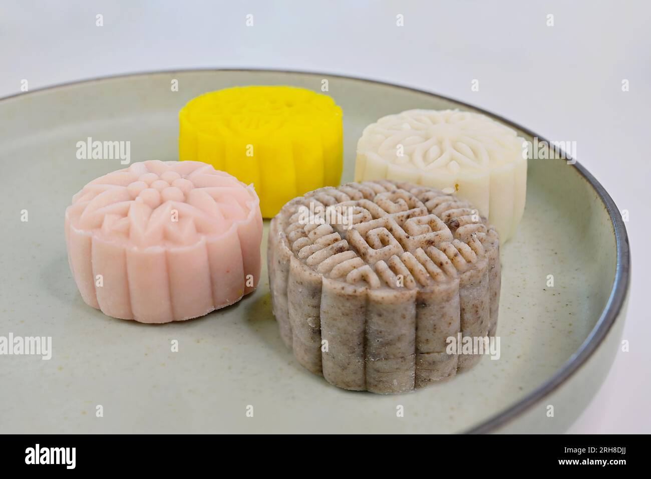 An assortment of colorful mini snow skin mooncakes on a green serving ...