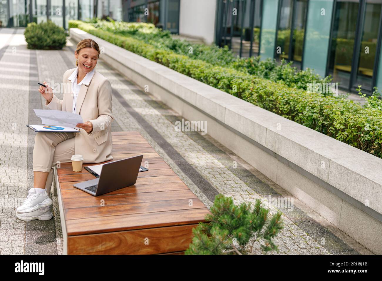 Woman analyst working with documents and use laptop sitting outside on ...