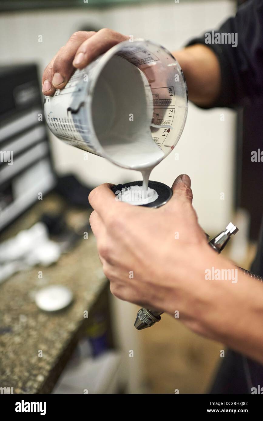 Hands of a young unrecognizable man pouring paint into a spray paint ...