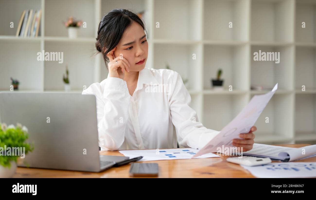 A professional Asian businesswoman reading report with a doubtful face ...
