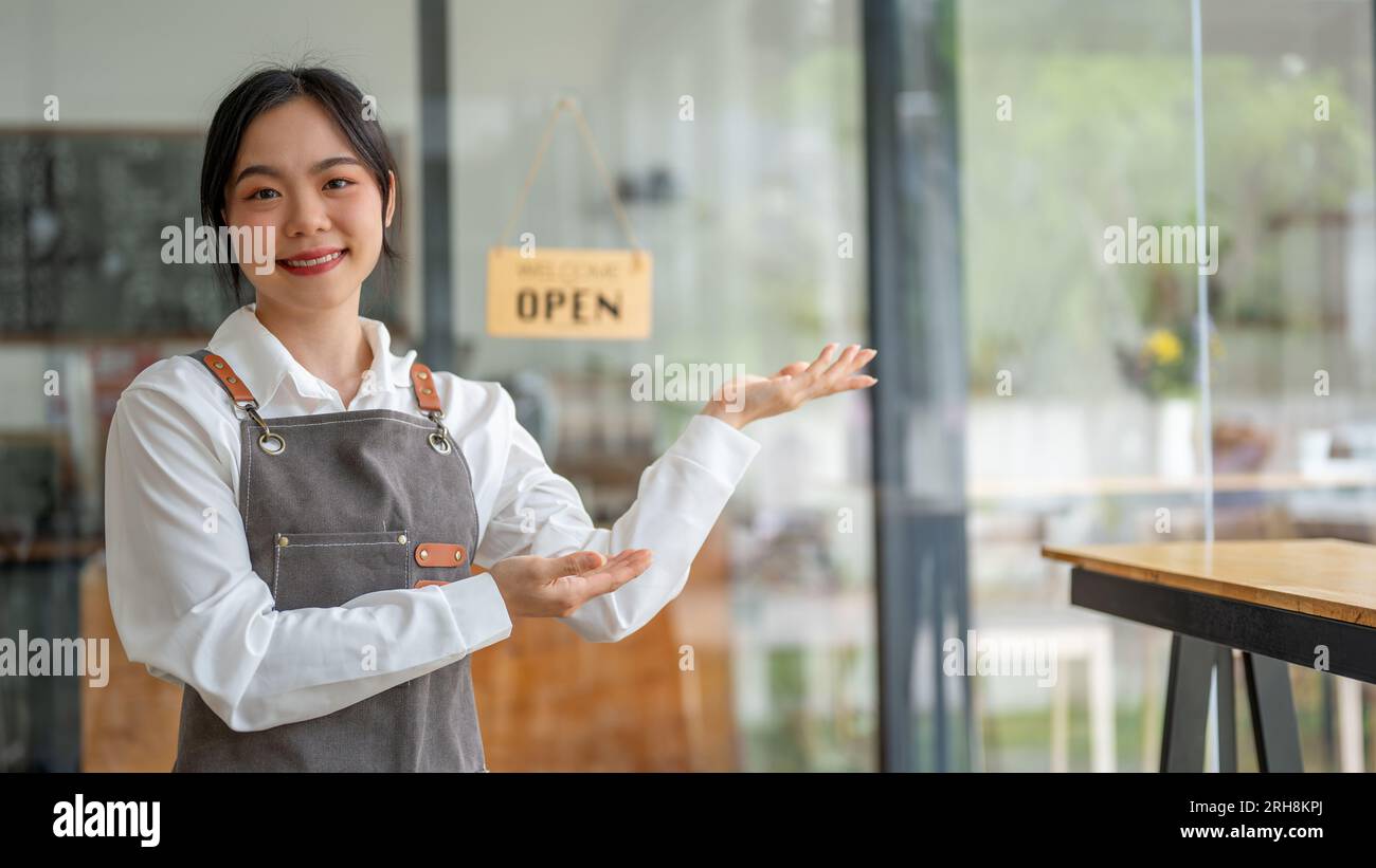 A pretty and smiling young Asian female cafe staff or small business ...