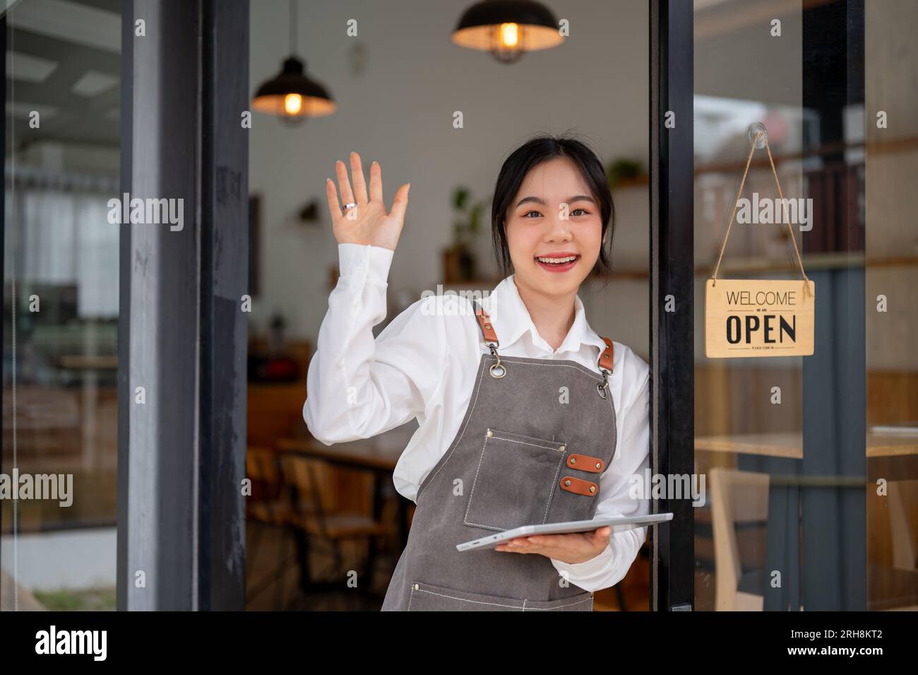 A friendly and cheerful Asian female coffee shop or restaurant staff in ...