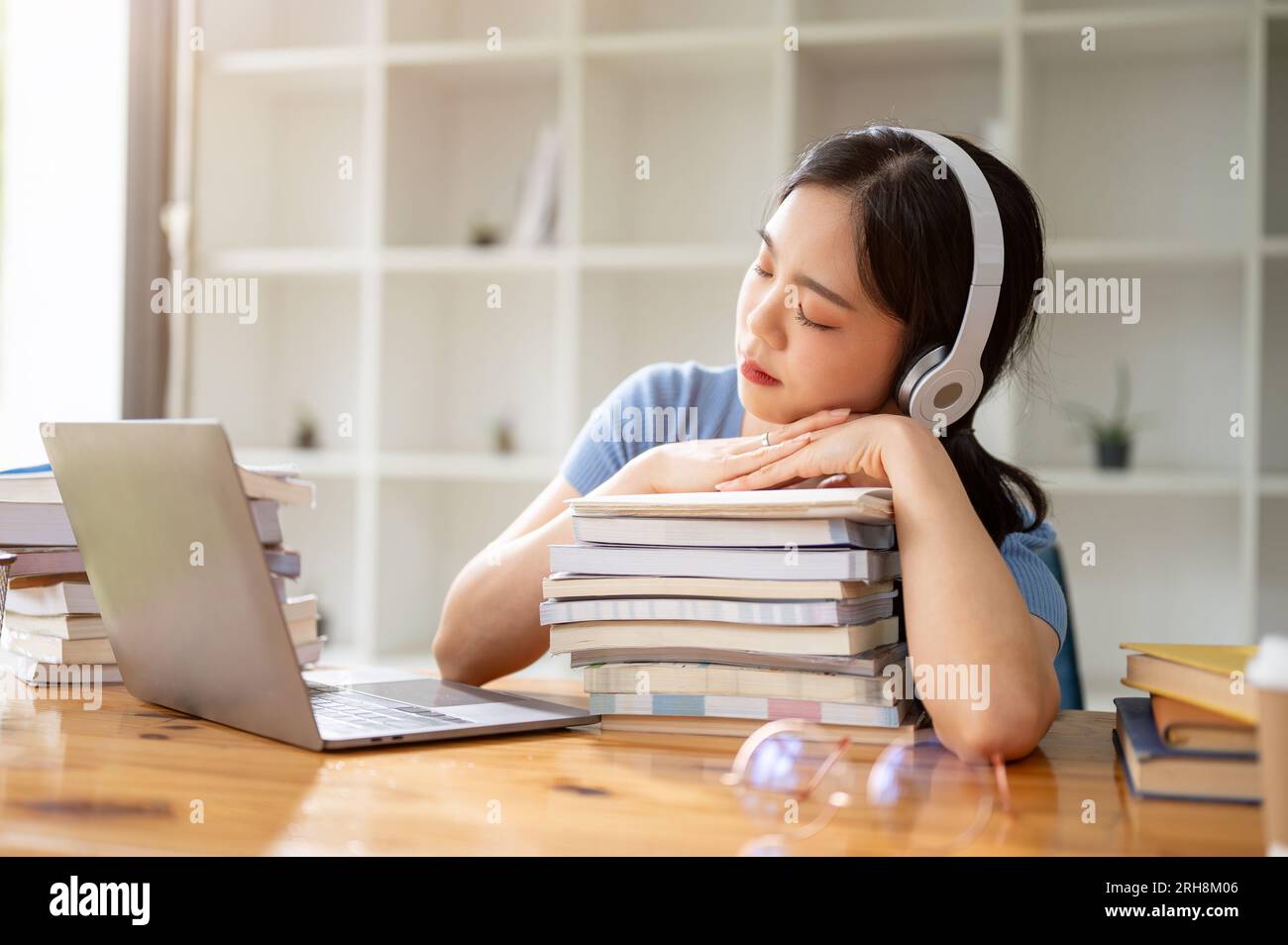 A beautiful Asian girl student is listening to music through her ...