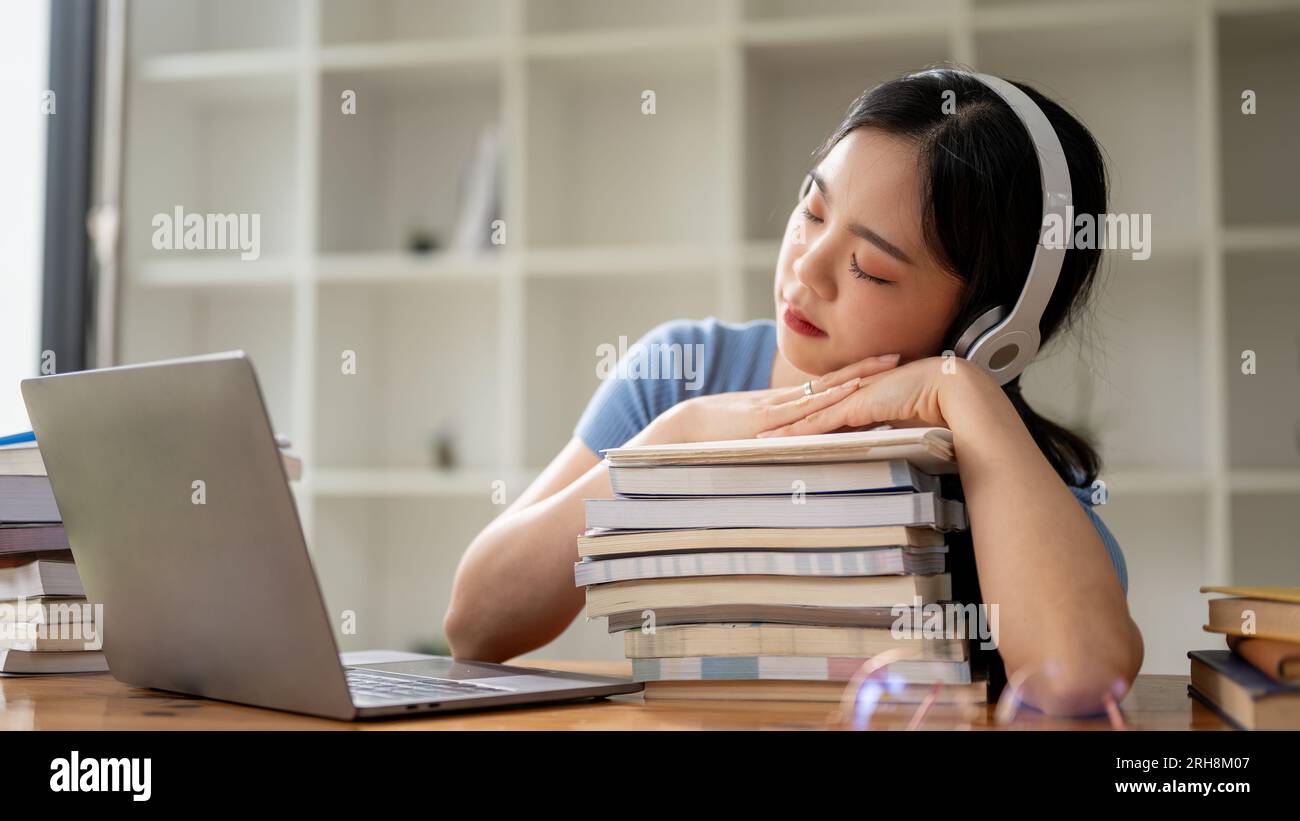 A beautiful, charming Asian girl student is listening to music through ...