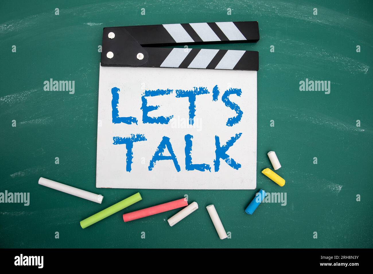 Let's talk. Movie clapper and colored pieces of chalk on a green ...