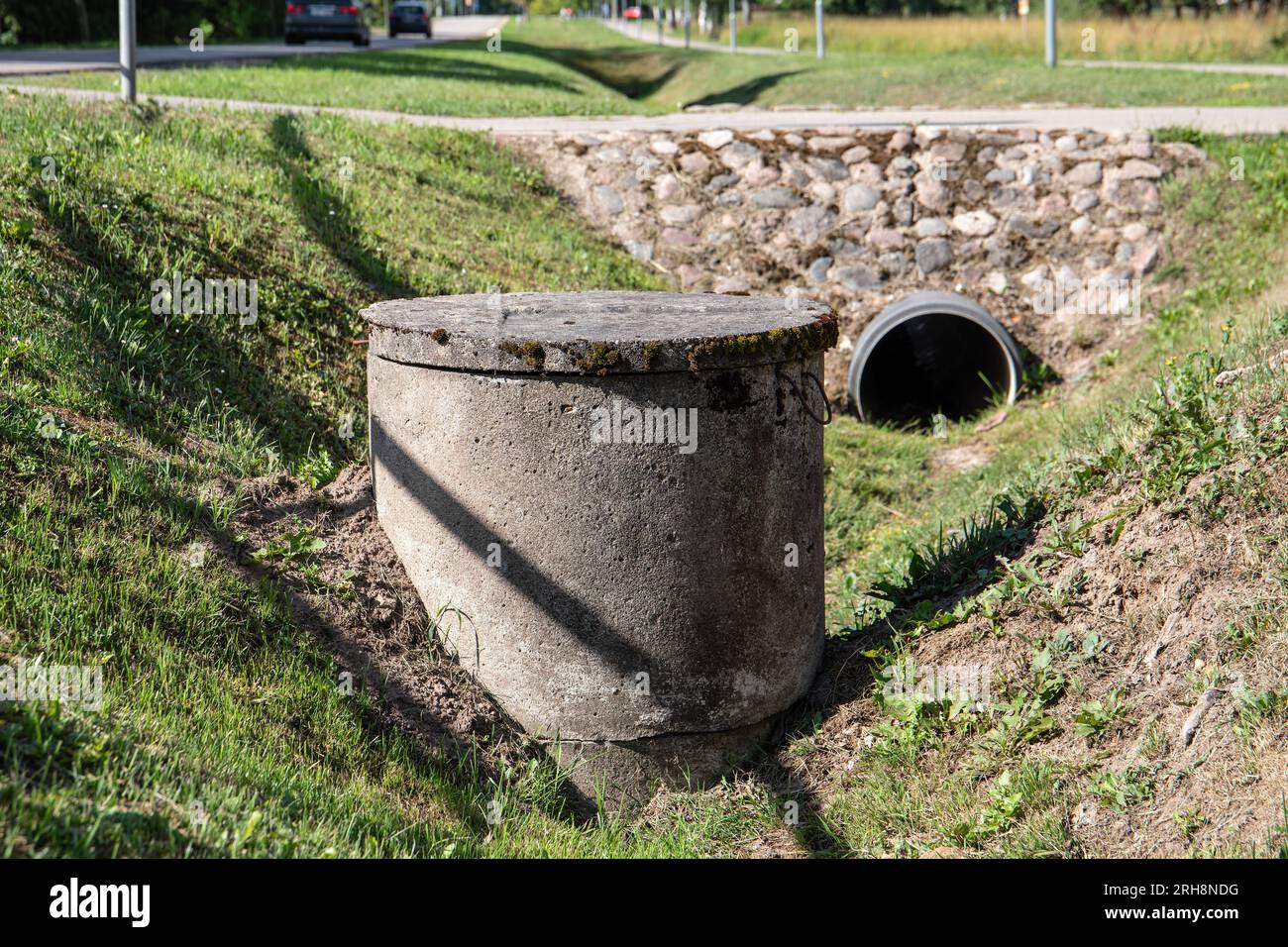 A sewage ditch and a concrete well with a concrete cover Stock Photo ...