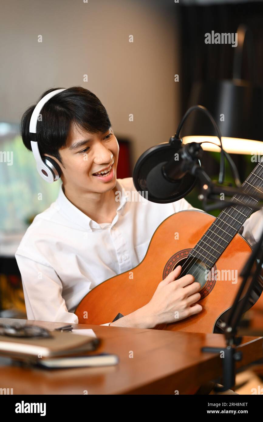 Happy asian man singing song and playing the guitar while streaming ...
