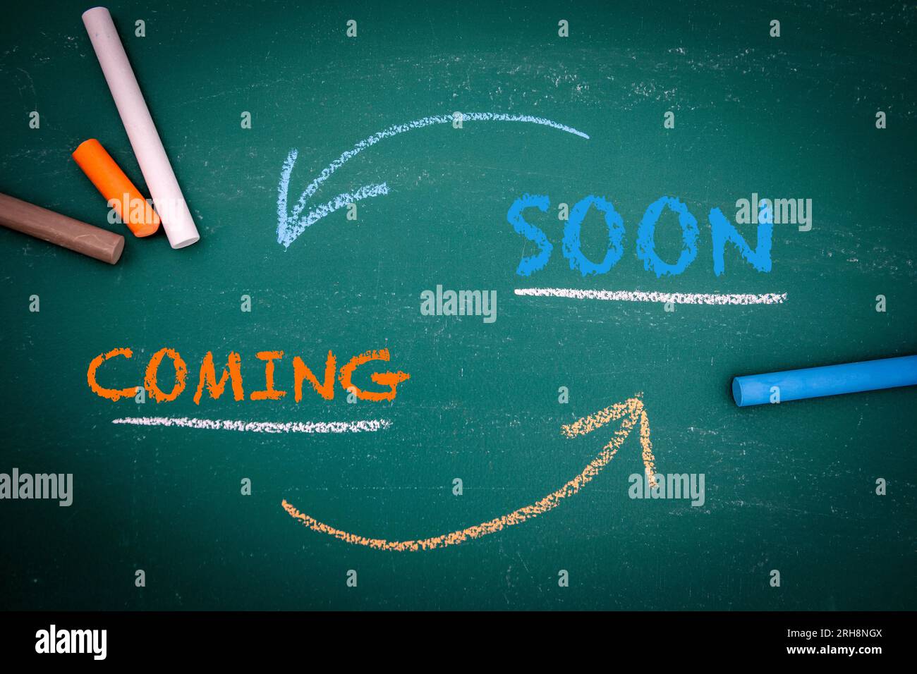 Coming Soon Concept. Text and colored pieces of chalk on a green ...