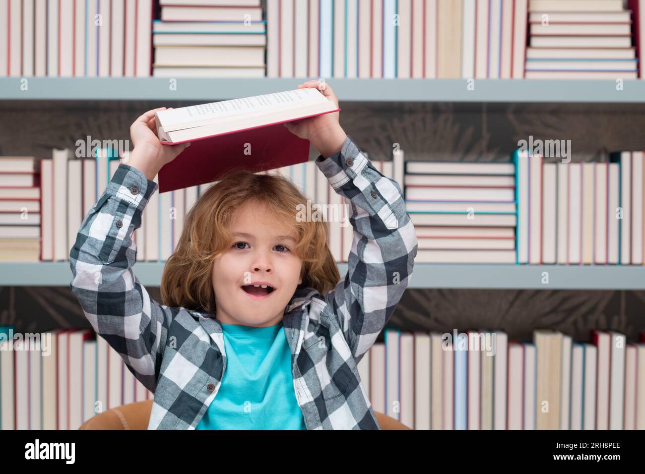 School child studying in school library. Portrait of child reading in ...