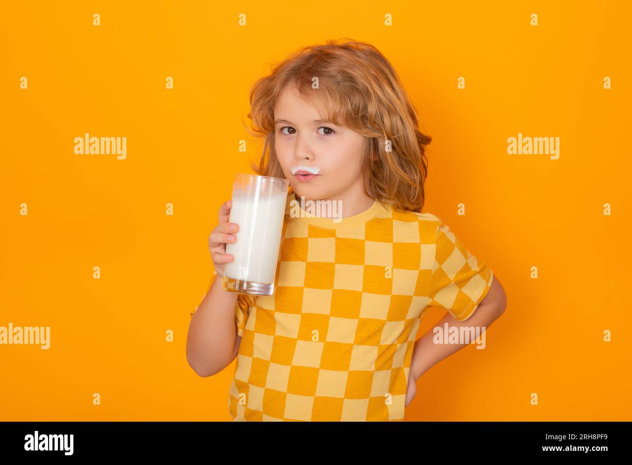 Small boy drink a glass of milk with funny emotions on yellow ...