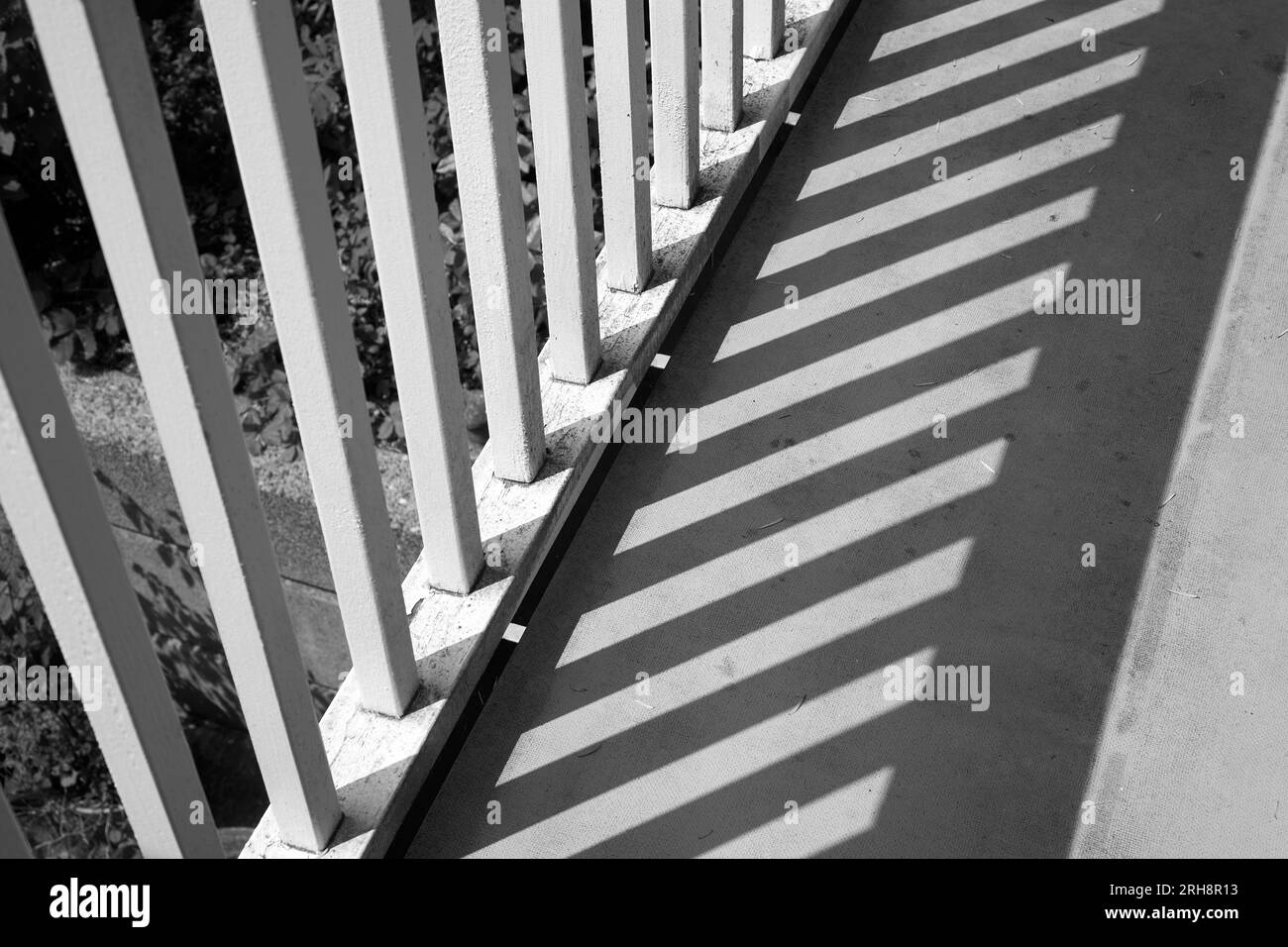 Wooden balcony railings casting shadows, black and white, oblique lines ...