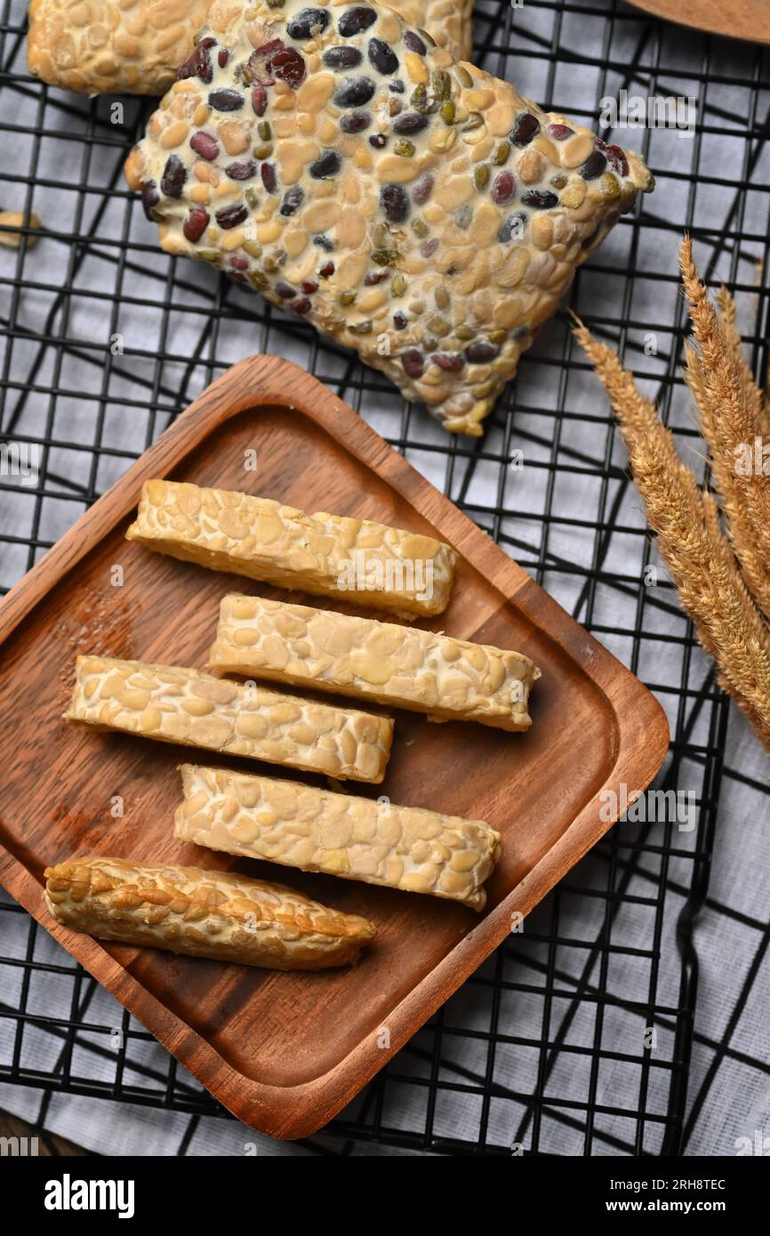 Sliced raw tempeh on wooden plate. Tempeh or Tempe made from fermented ...