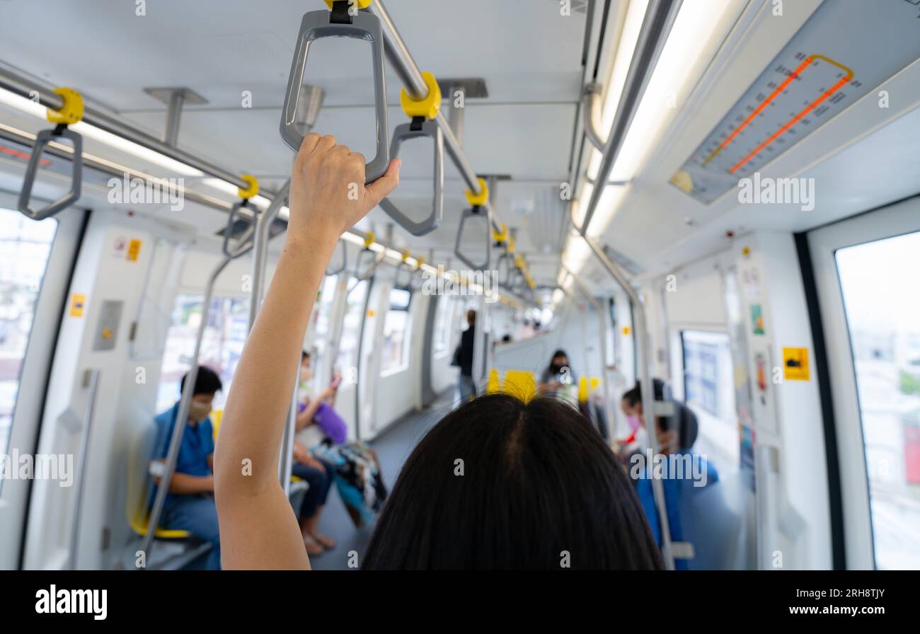 Woman hand firm grip safety handrail in elevated monorail train. Mass transit system in modern ...
