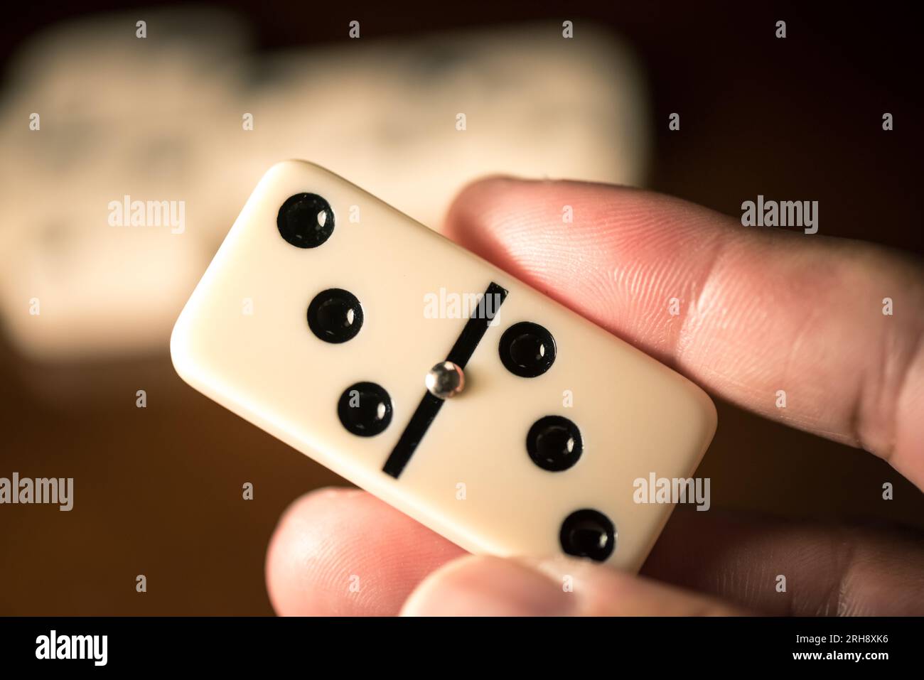 Close up Domino tiles in hand. Dominoes is one of the most famous ...