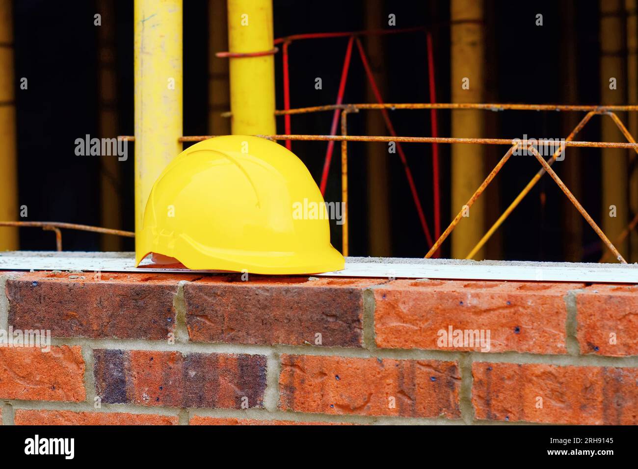 Yellow hard hat on top of red brick wall Stock Photo - Alamy