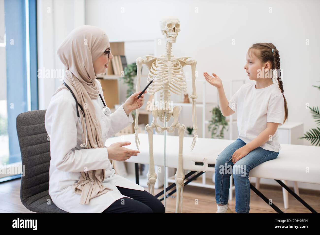 Adorable caucasian child in jeans asking female doctor about anatomy ...