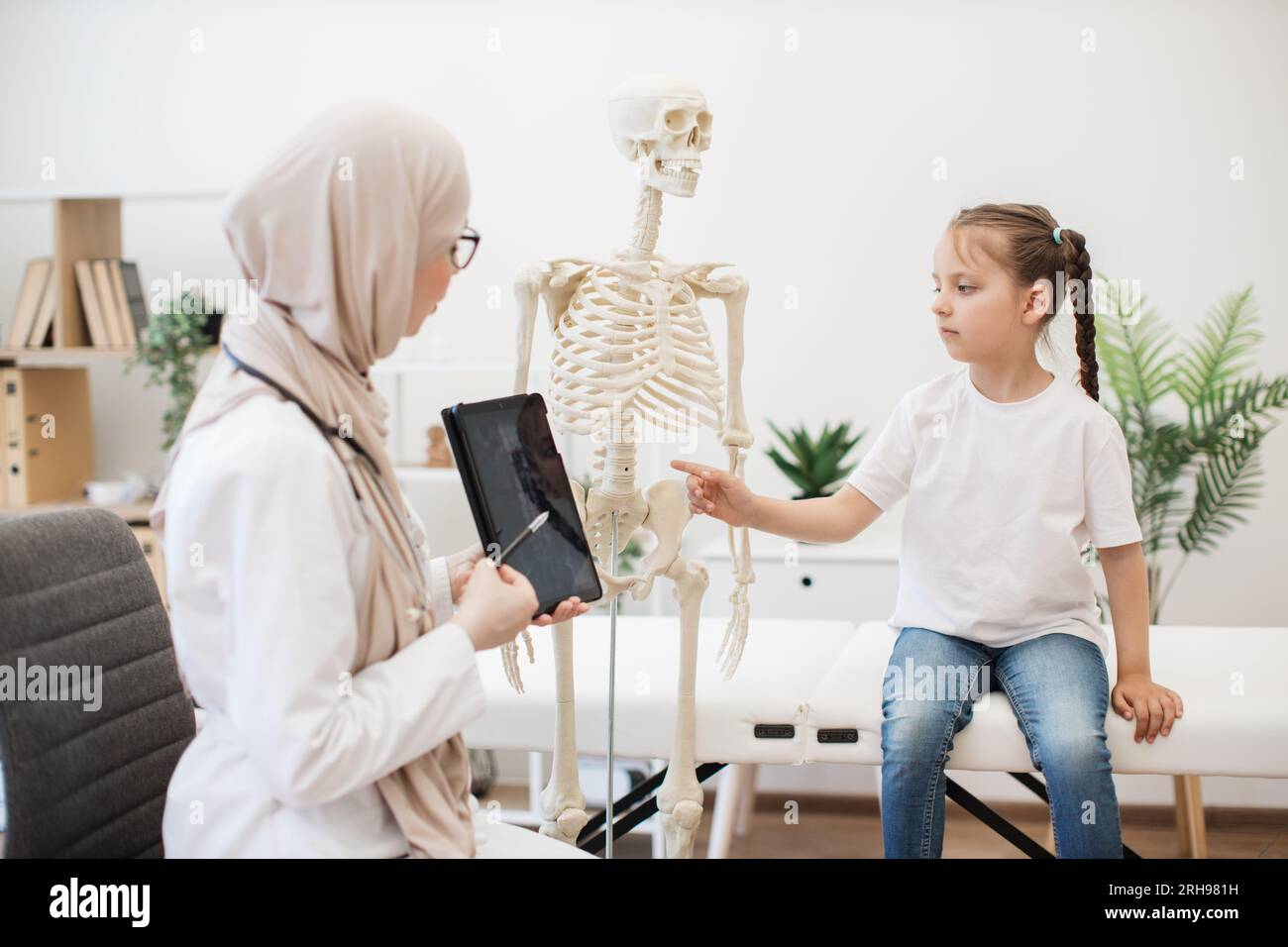 Child inspecting skeleton while physician analyzing CT scan Stock Photo ...