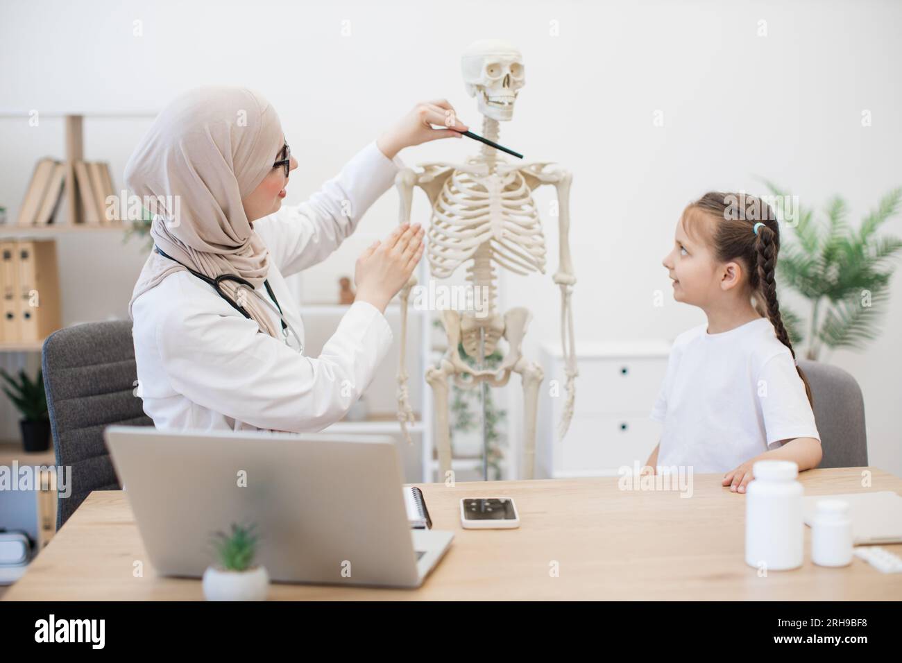 Medical person describing shoulder bones to kid via skeleton Stock ...
