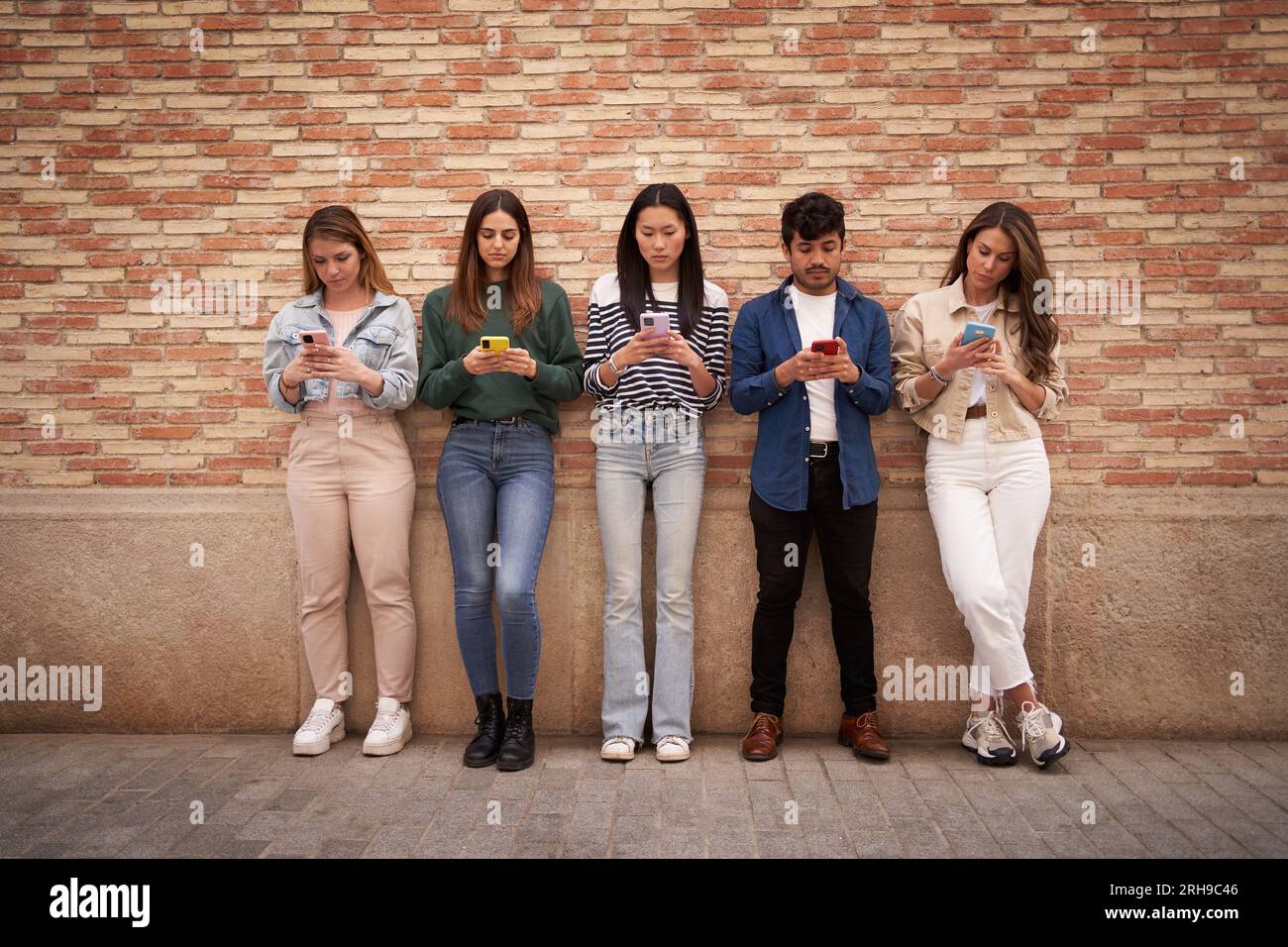 Multiracial serious group young generation z leaning on brick wall ...