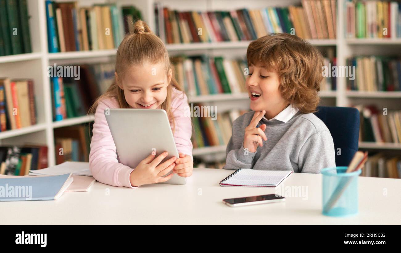 Two primary school kids sitting together at desk in classroom or ...