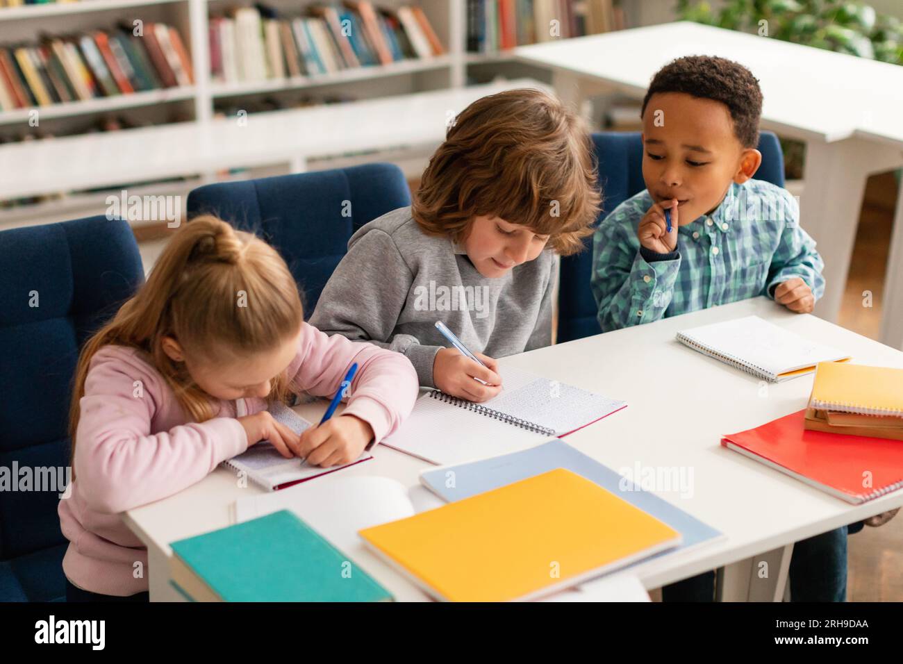 African american elementary schoolboy peeking on classmate's answer ...