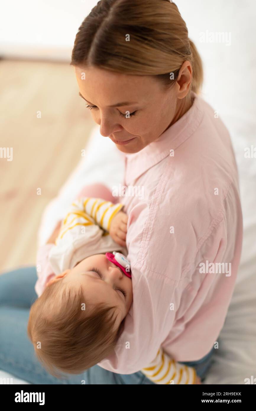 Loving mother holding her sleeping infant daughter on hands, lulling ...