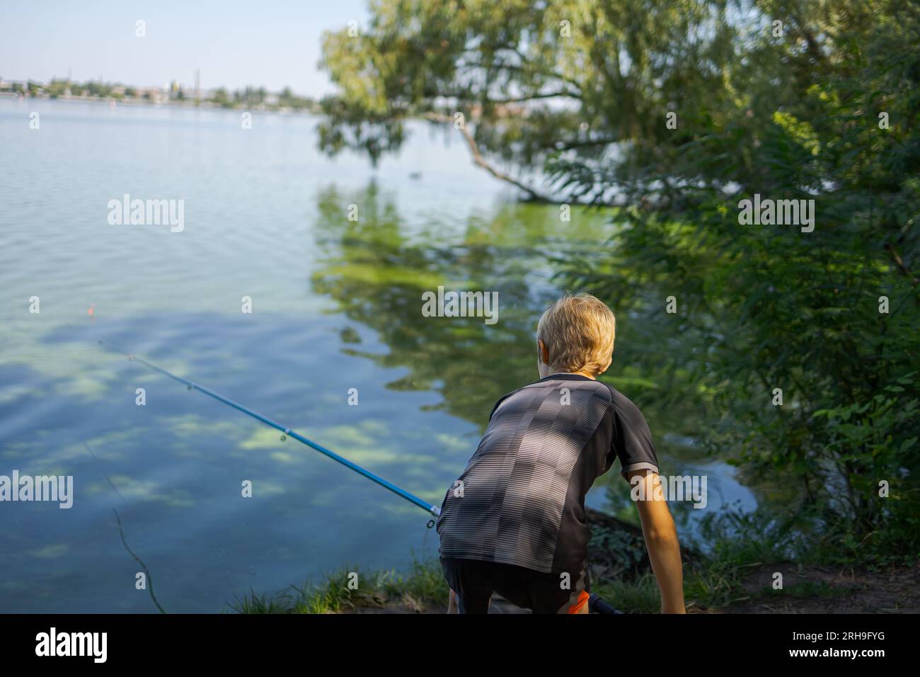 A teenager with his back turned is fishing with a cast rod. Sport ...