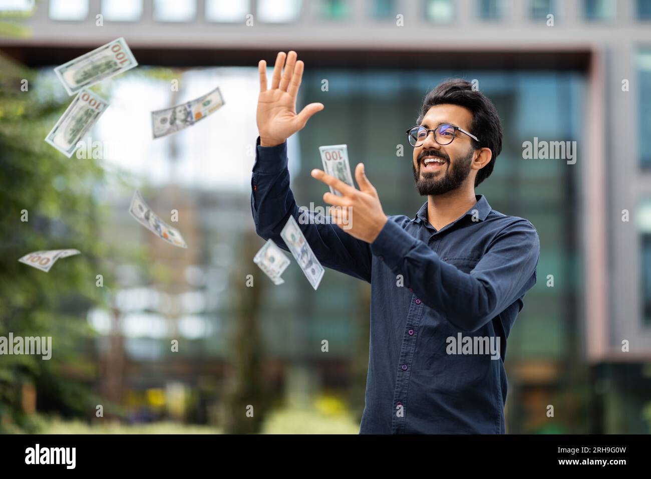 Overjoyed rich young indian businessman throwing money dollar banknotes ...