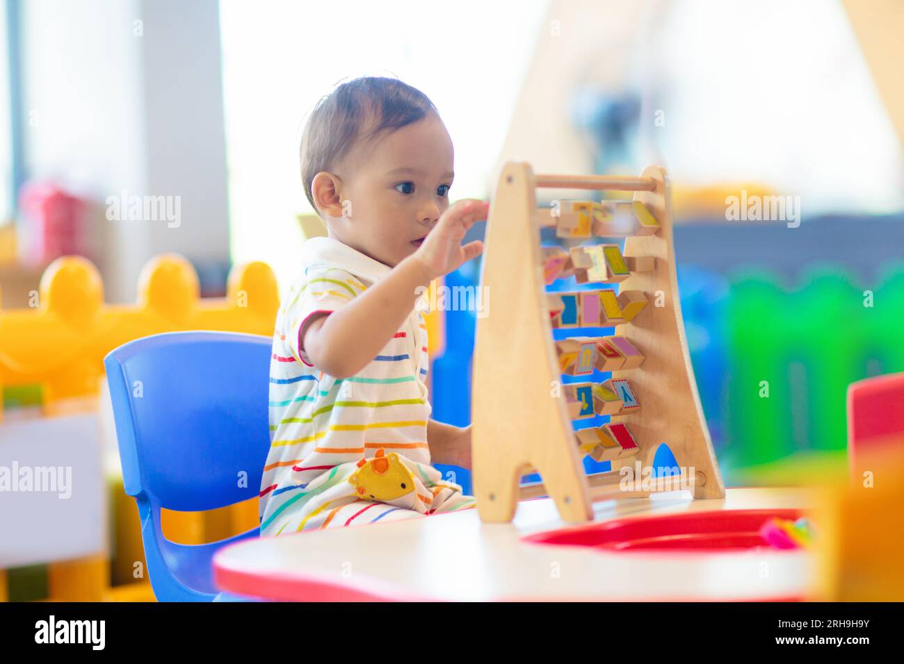 Adorable Asian baby boy in kindergarten or daycare. Child playing with ...