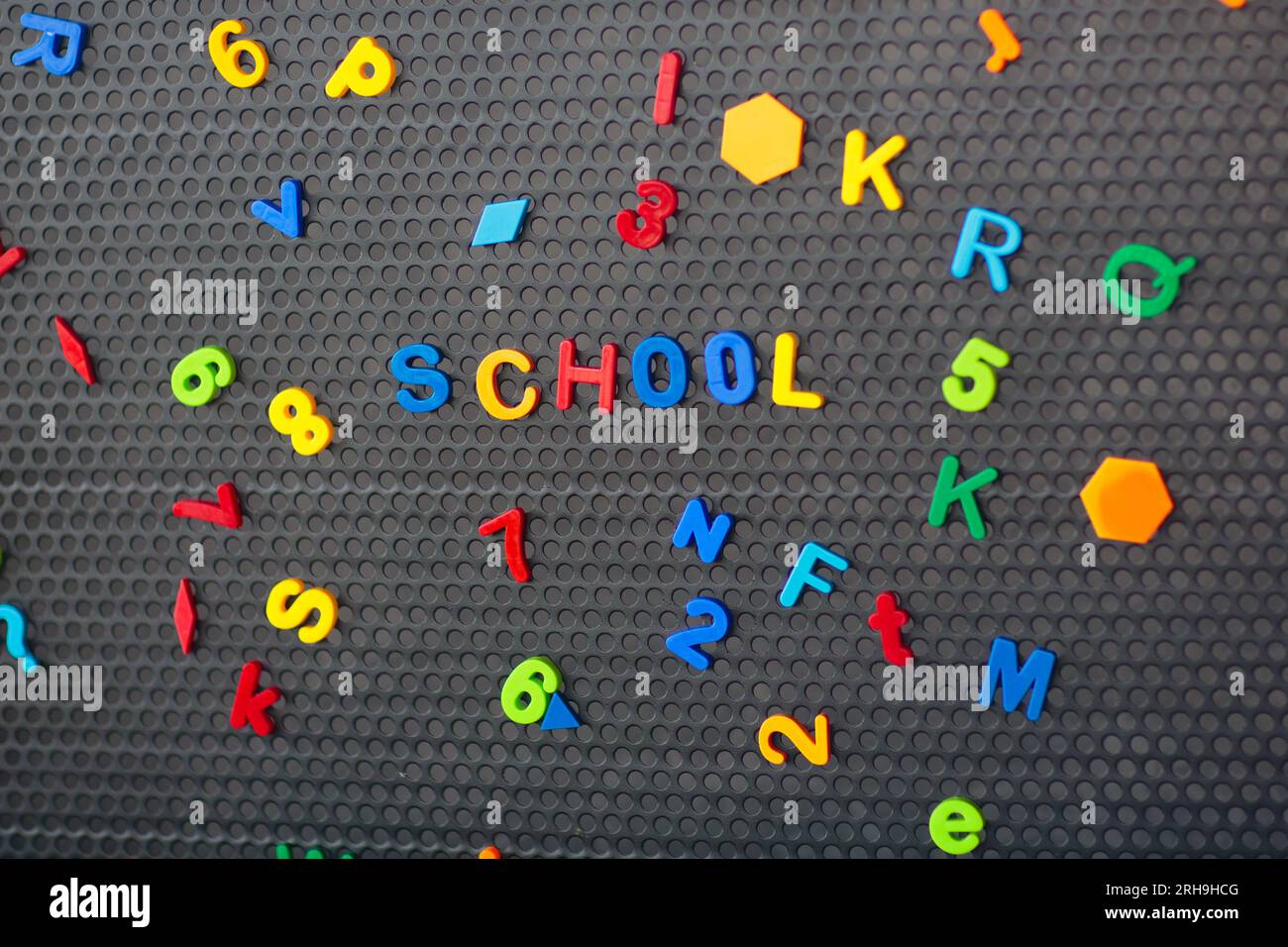 Boy spelling out the word school. Magnet letters on black board in ...