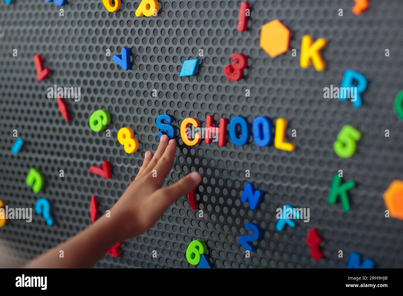 Boy spelling out the word school. Magnet letters on black board in ...