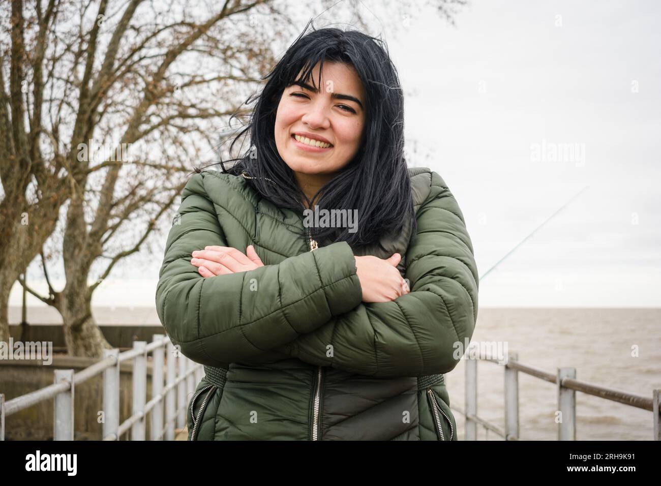 portrait of young latin woman standing on pier over river in Buenos ...