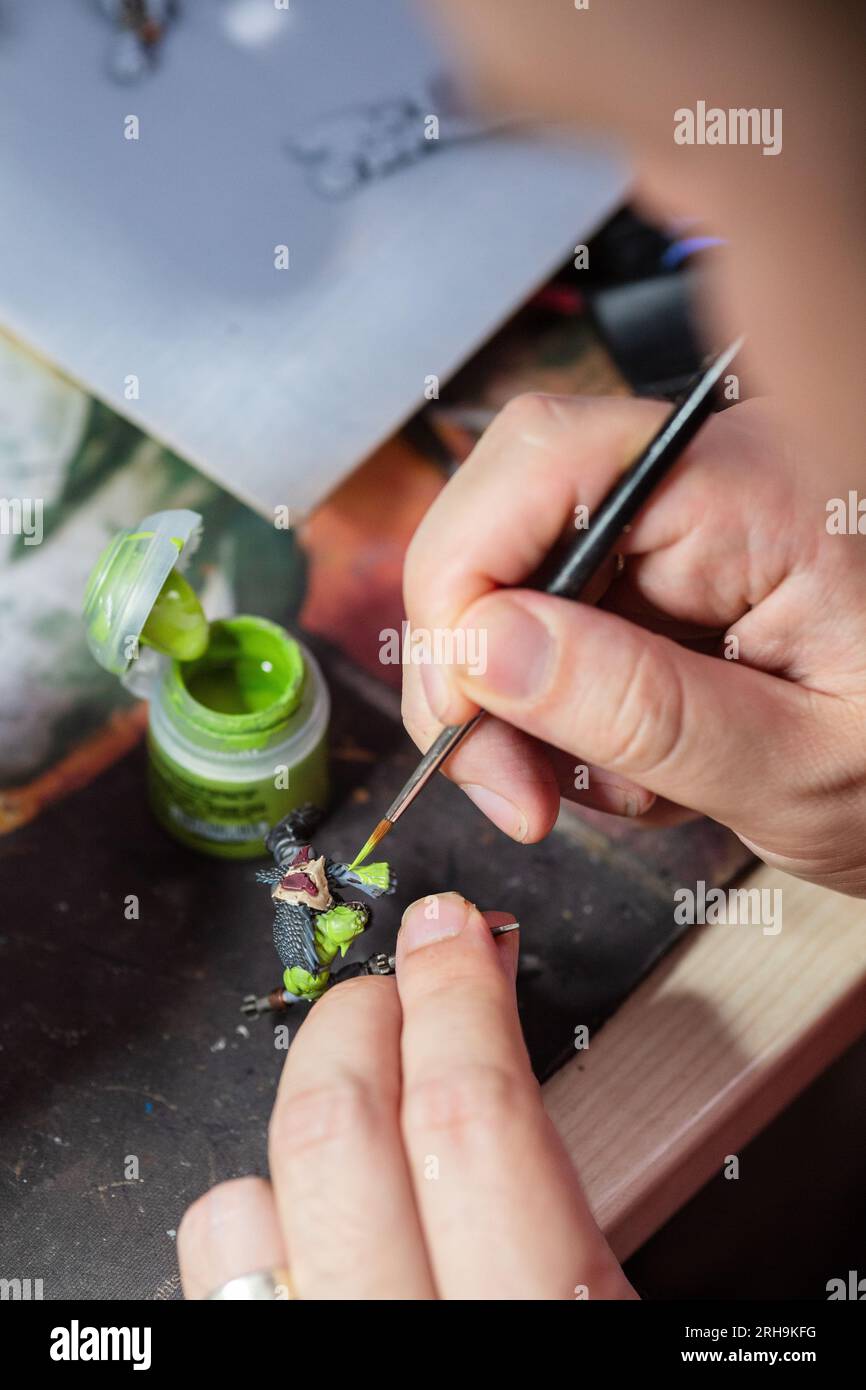 Close up of a man painting a Warhammer Squig Hog Boy with green paint ...