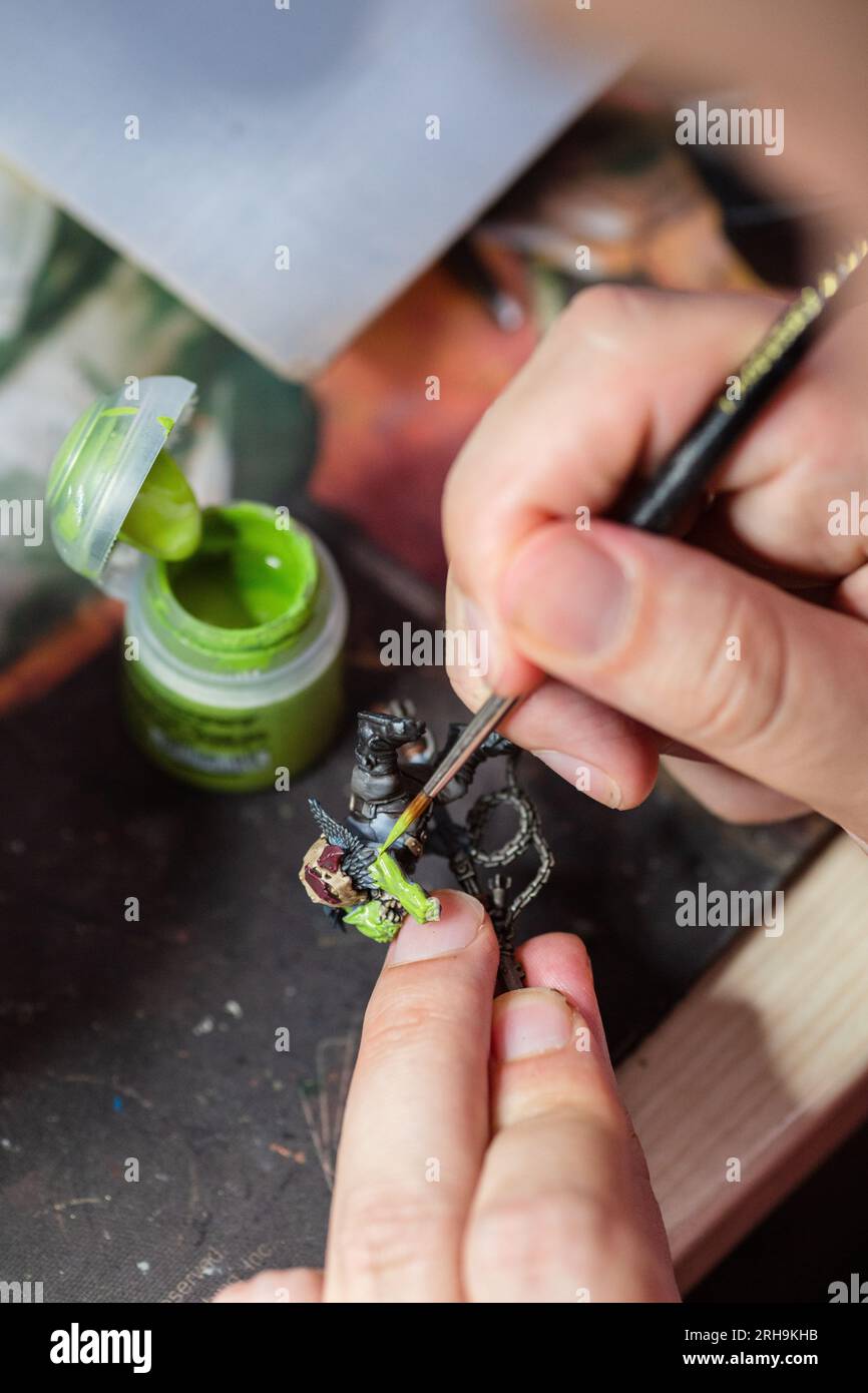 Close up of a man painting a Warhammer Squig Hog Boy with green paint ...