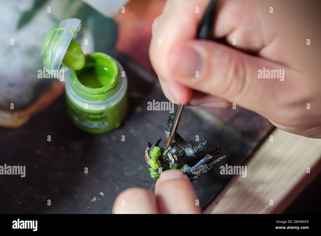 Close up of a man painting a Warhammer Squig Hog Boy with green paint ...