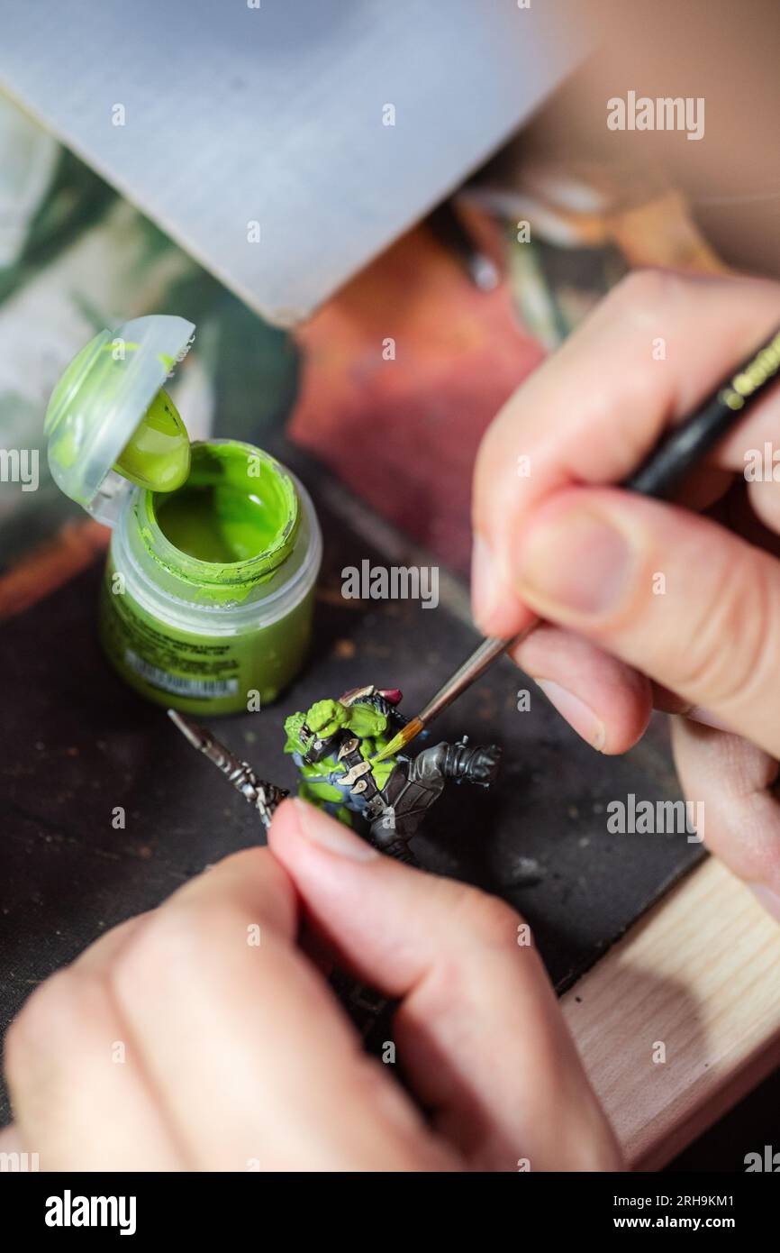 Close up of a man painting a Warhammer Squig Hog Boy with green paint ...