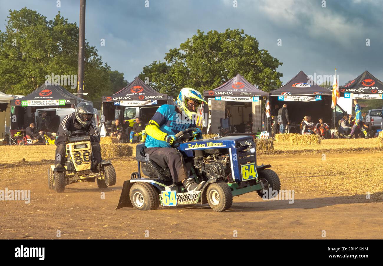 Racing lawn mower drivers bounce around a corner at sunrise after dring ...
