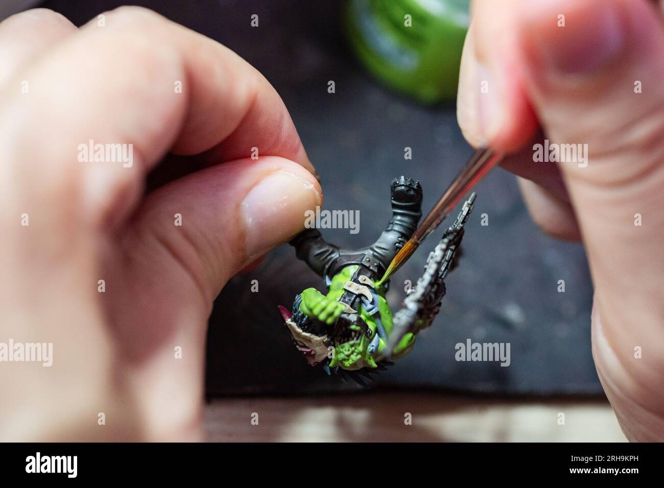 Close up of a man painting a Warhammer Squig Hog Boy with green paint ...