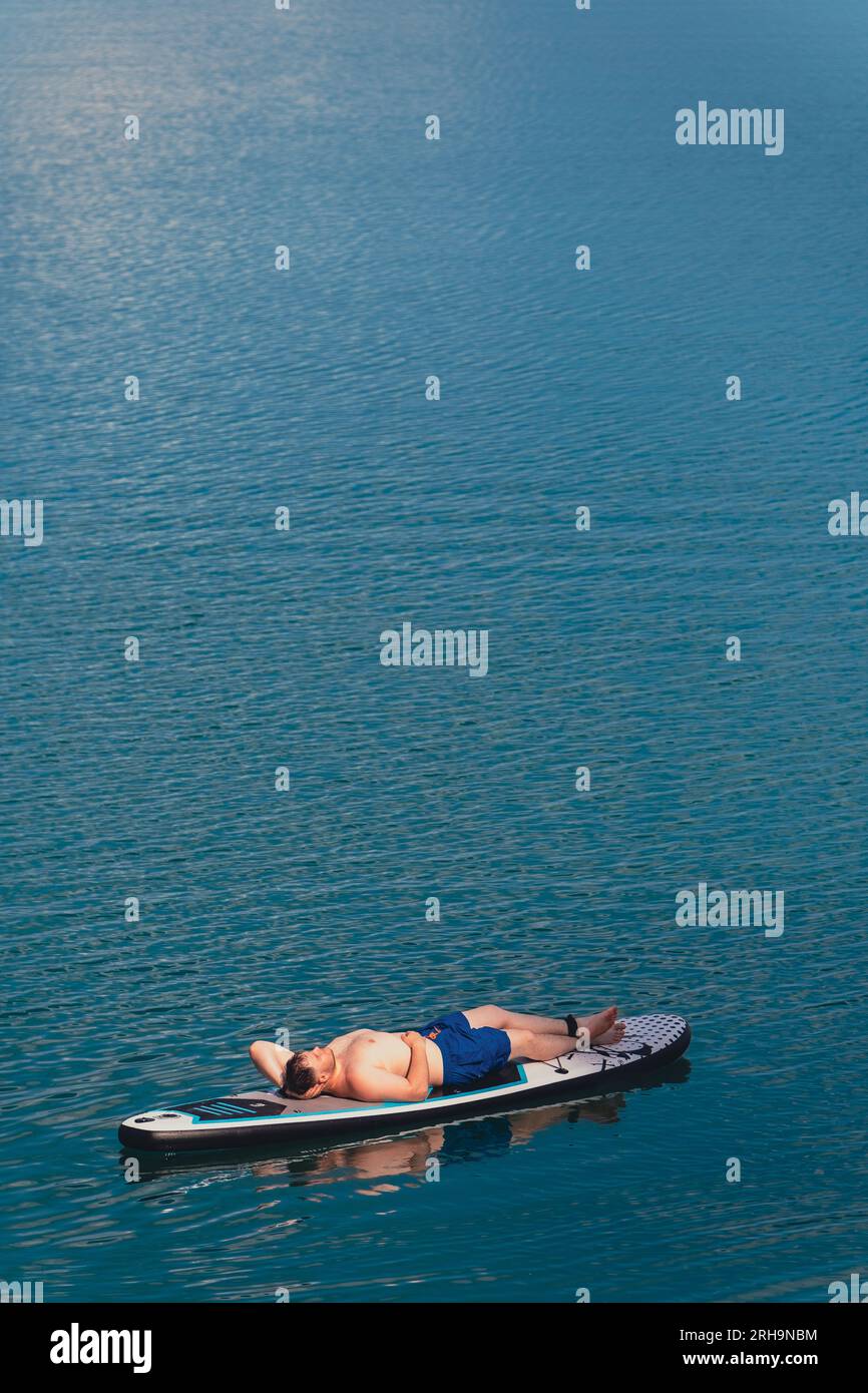 happy man lays down on supboard sunbathing Stock Photo - Alamy