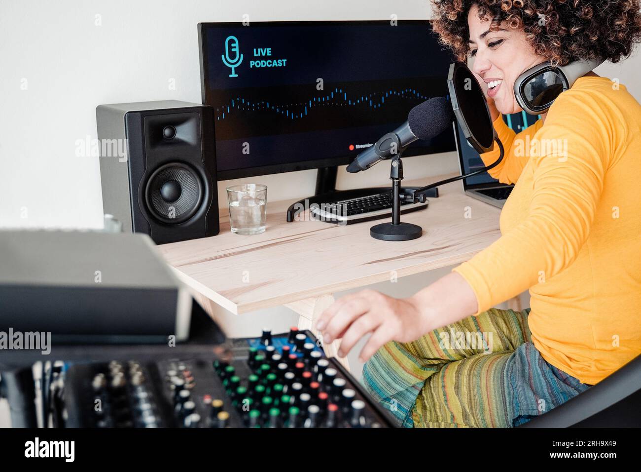 Happy Afro woman recording podcast radio show while broadcasting inside ...