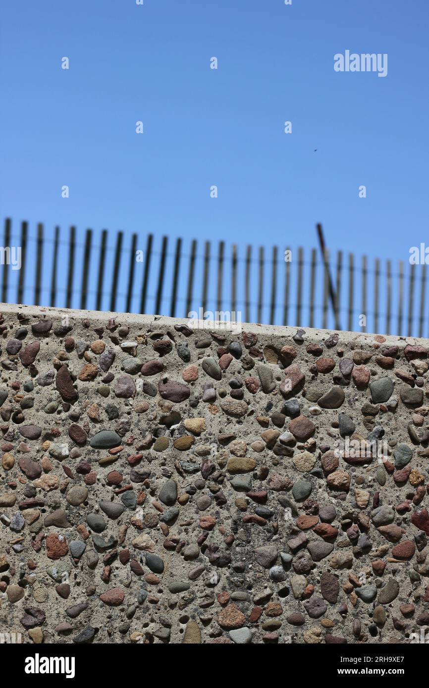 A simple wooden fence standing on top of a concrete pebble wall Stock ...